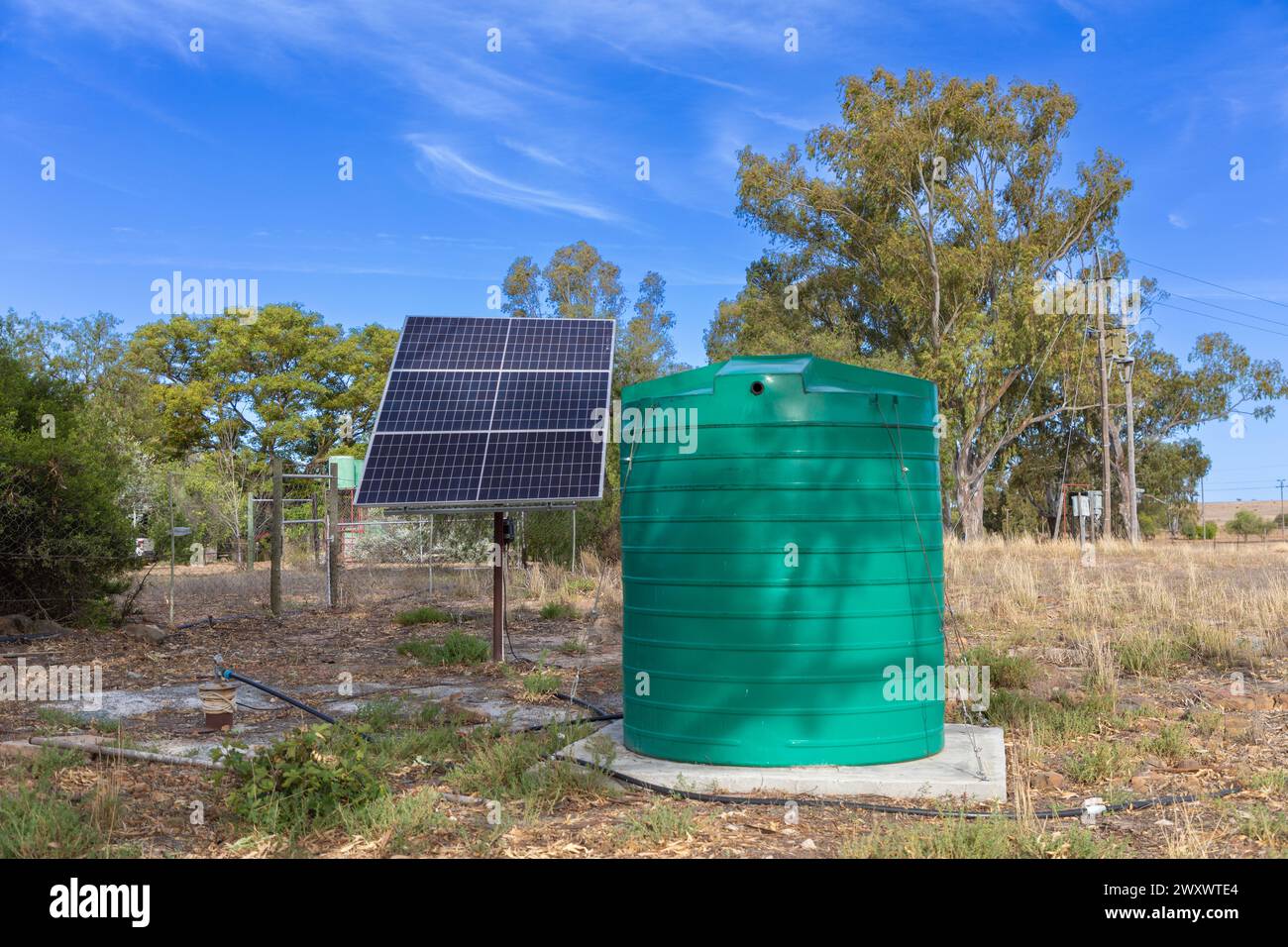 Large green plastic storage tank with solar panes connected to a ...
