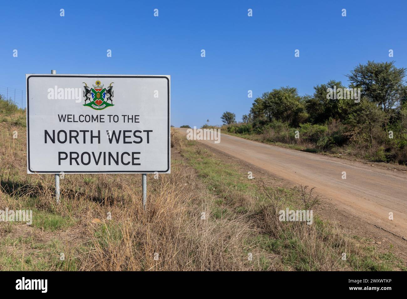 Welcome to North West Province Sign with a gravel road to the right of ...