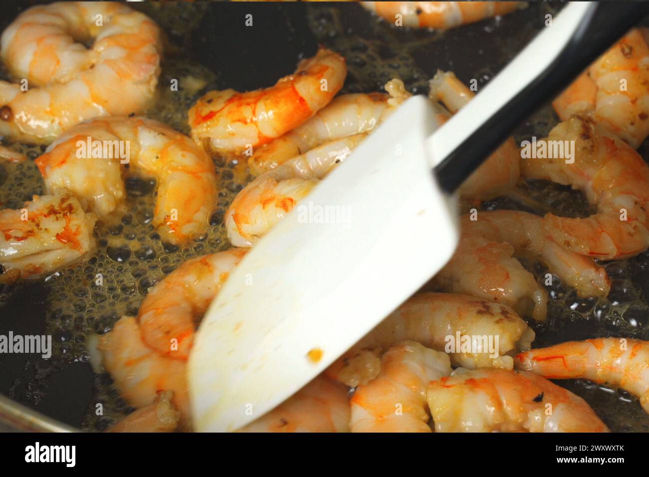 Fresh shrimp being cooked in a sizzling pan on the stove, with steam ...