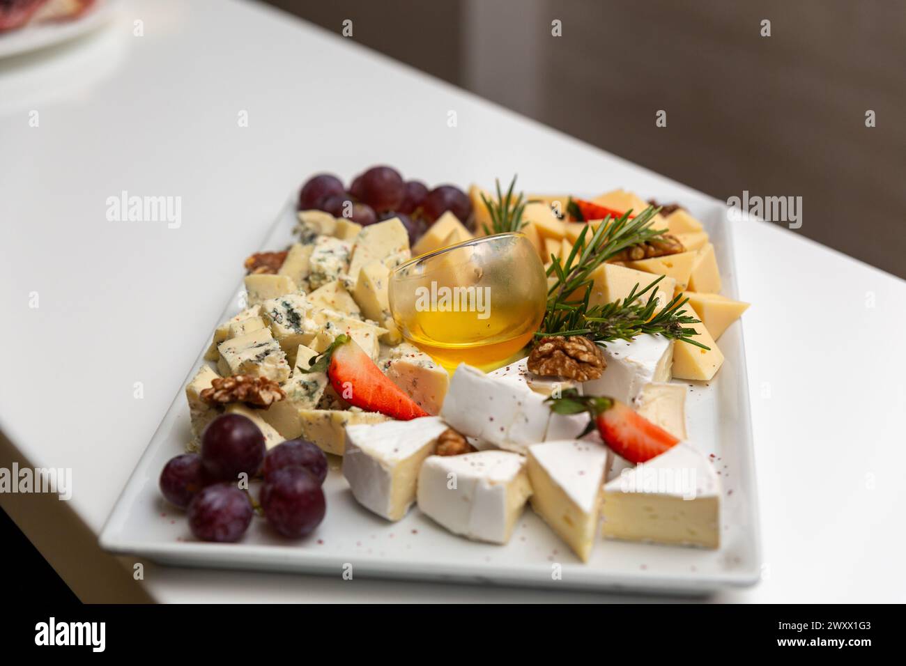 Cheese plate with fruit and spices on a white table. Different cheeses ...