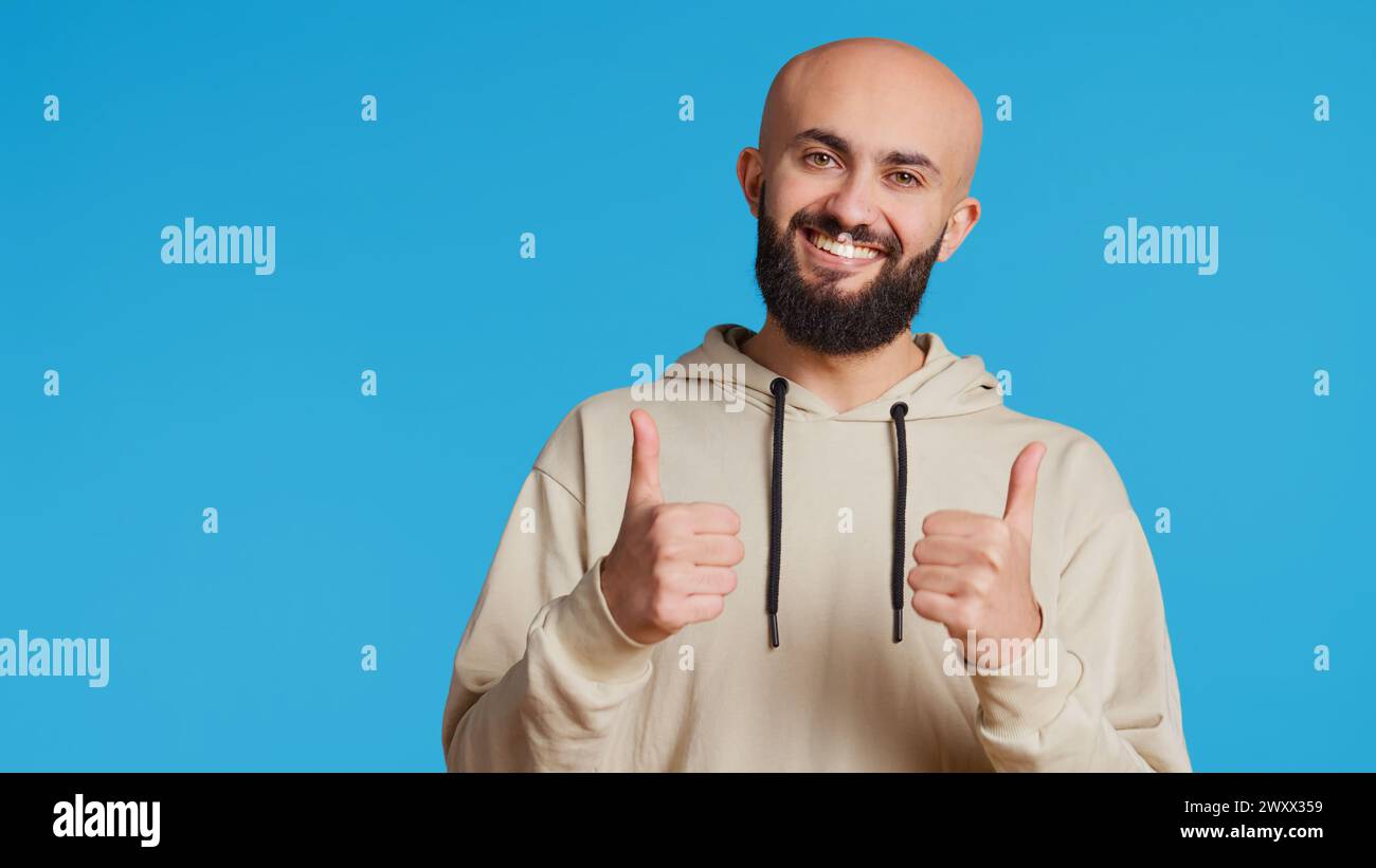 Middle eastern person giving thumbs up on camera, feeling cheerful and ...