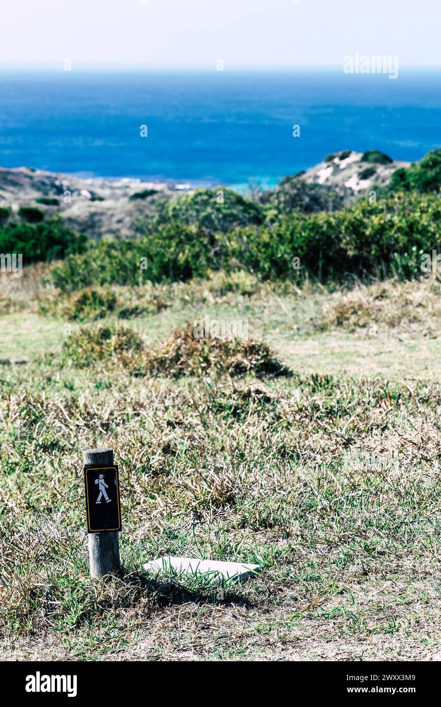 A trail marker with a hiker symbol stands alongside a path at Cape ...