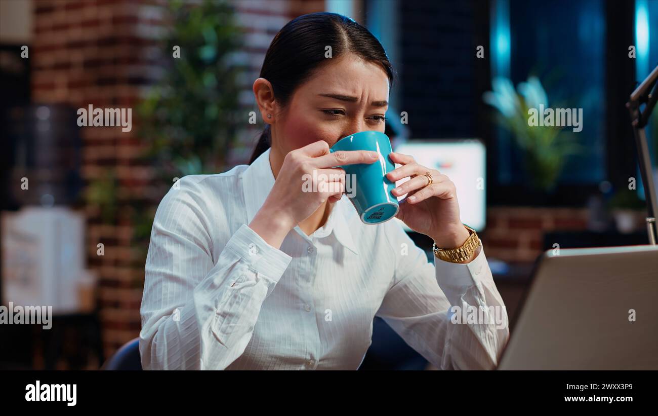 Employee tired while writing emails at computer desk, trying to freshen ...