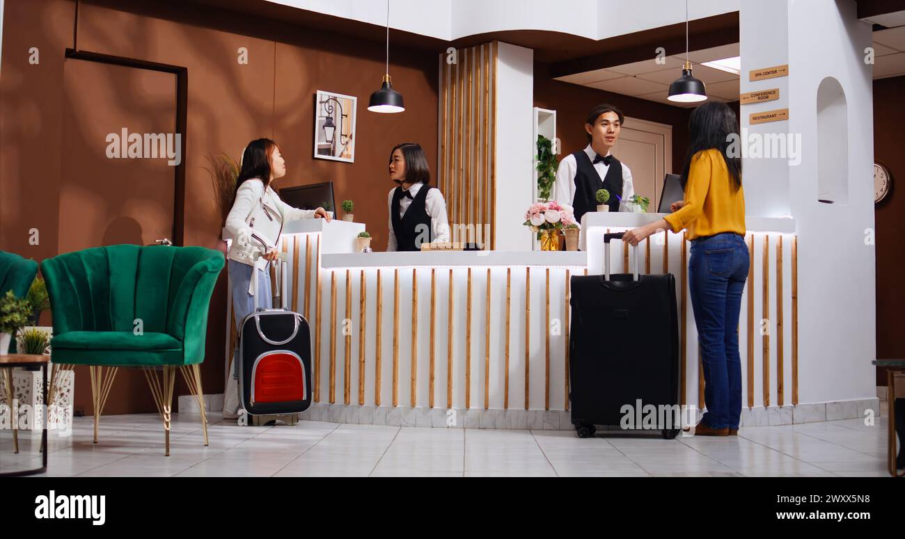 Asian guests approach reception to ask about accommodation, arriving at ...