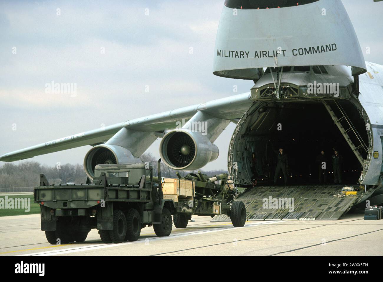 A truck is used to push a 155 mm M198 Howitzer toward the loading ramp ...