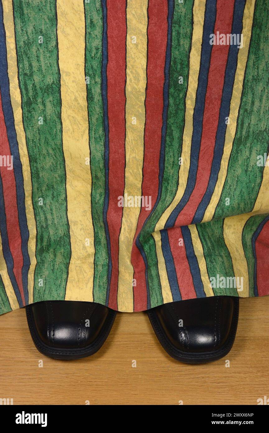 Black dress shoes peeking from behind colorful curtains on beige hard ...