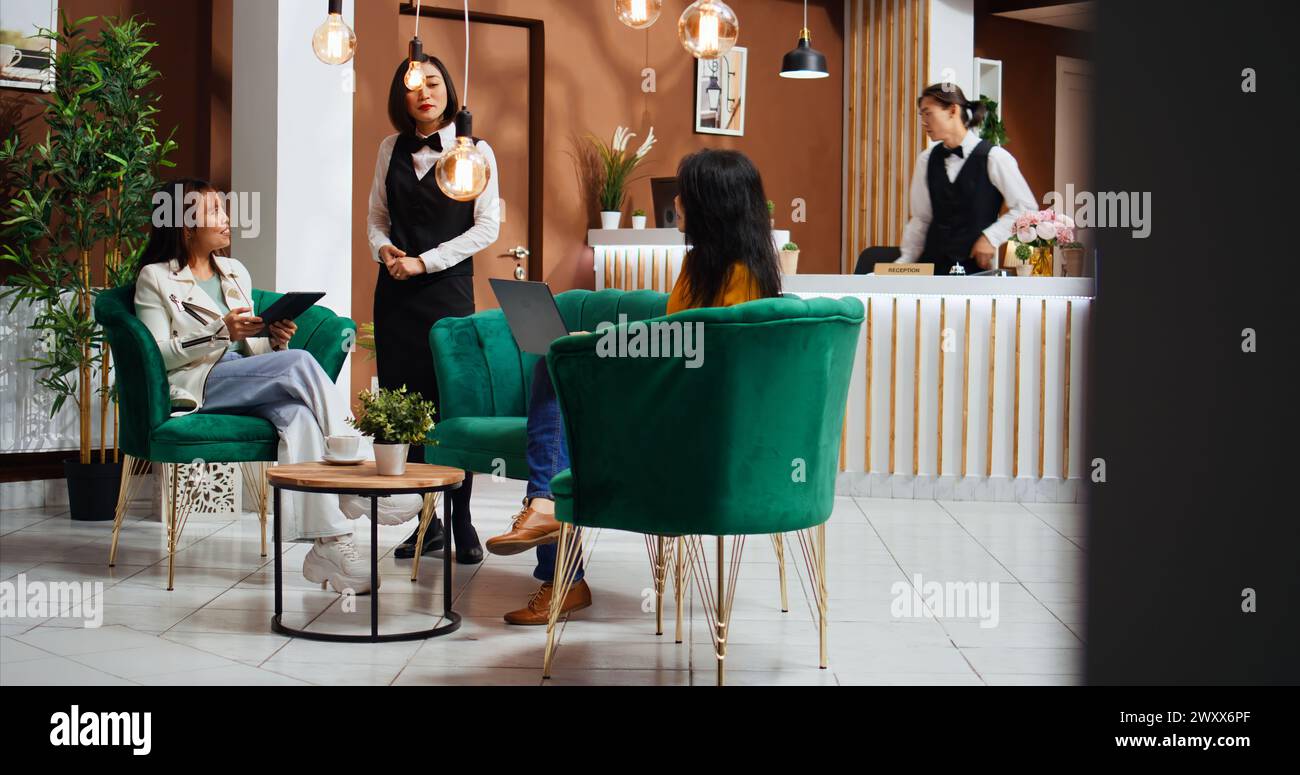 Receptionist providing concierge services for guests in lobby, staff ...