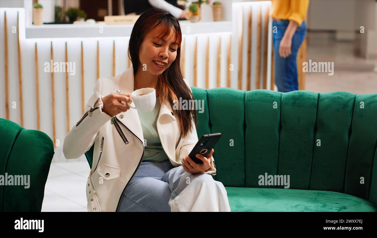 Modern person taking advantage of free wifi in lobby, using smartphone to pass time before going ...