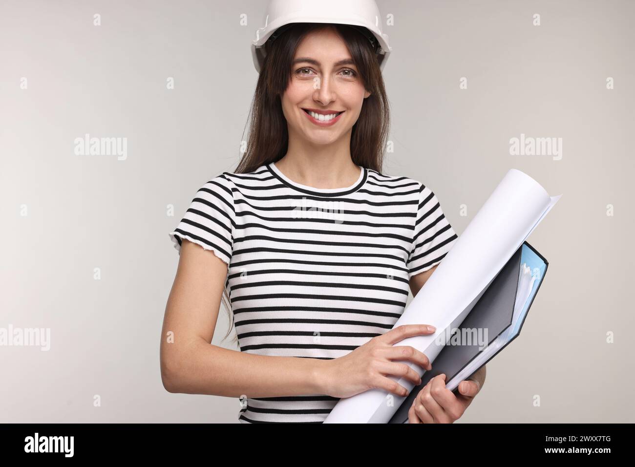 Architect in hard hat with draft and folder on light grey background ...