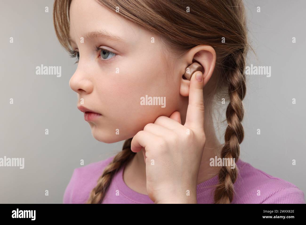 Little girl with hearing aid on grey background, closeup Stock Photo ...