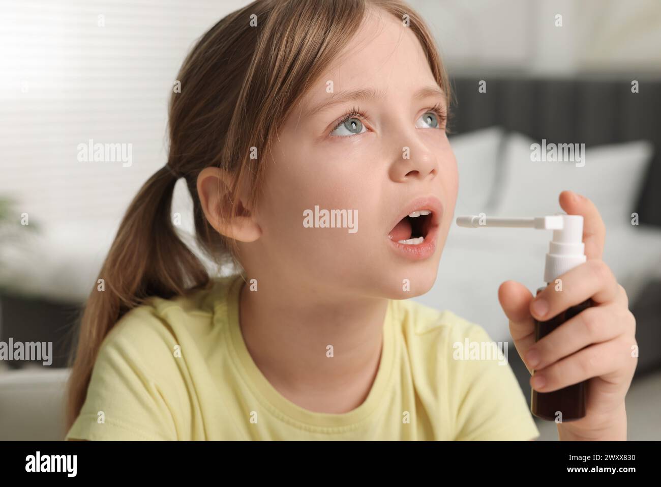 Little girl using throat spray at home Stock Photo - Alamy