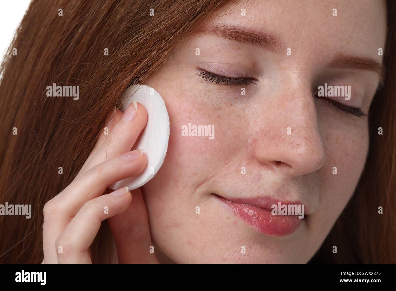 Beautiful woman with freckles wiping face on white background, closeup ...