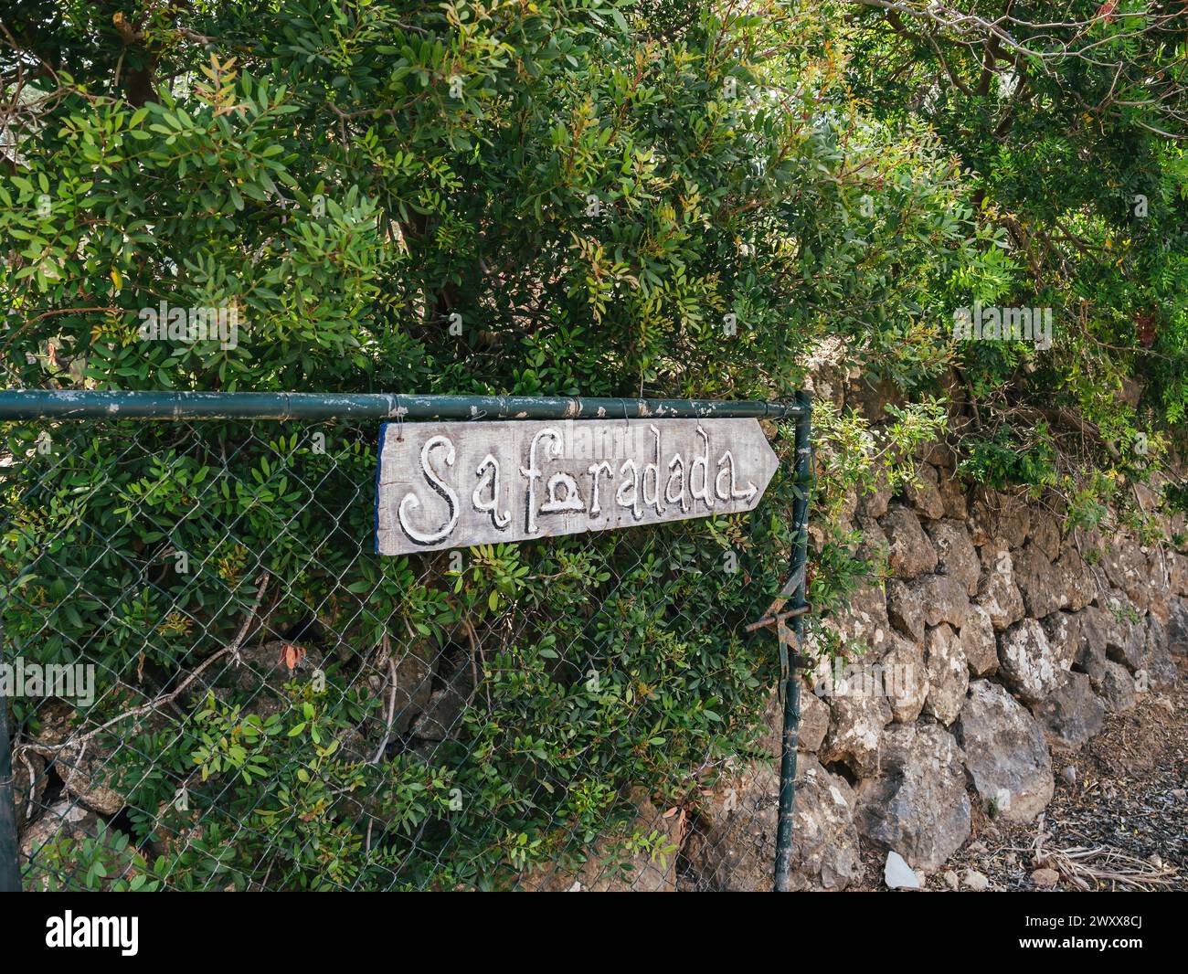Rustic handmade sign reading Sa forada mounted on a metal fence with ...