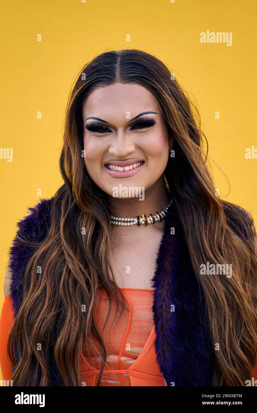 Portrait of smiling transgender young with yellow background. Happy ...