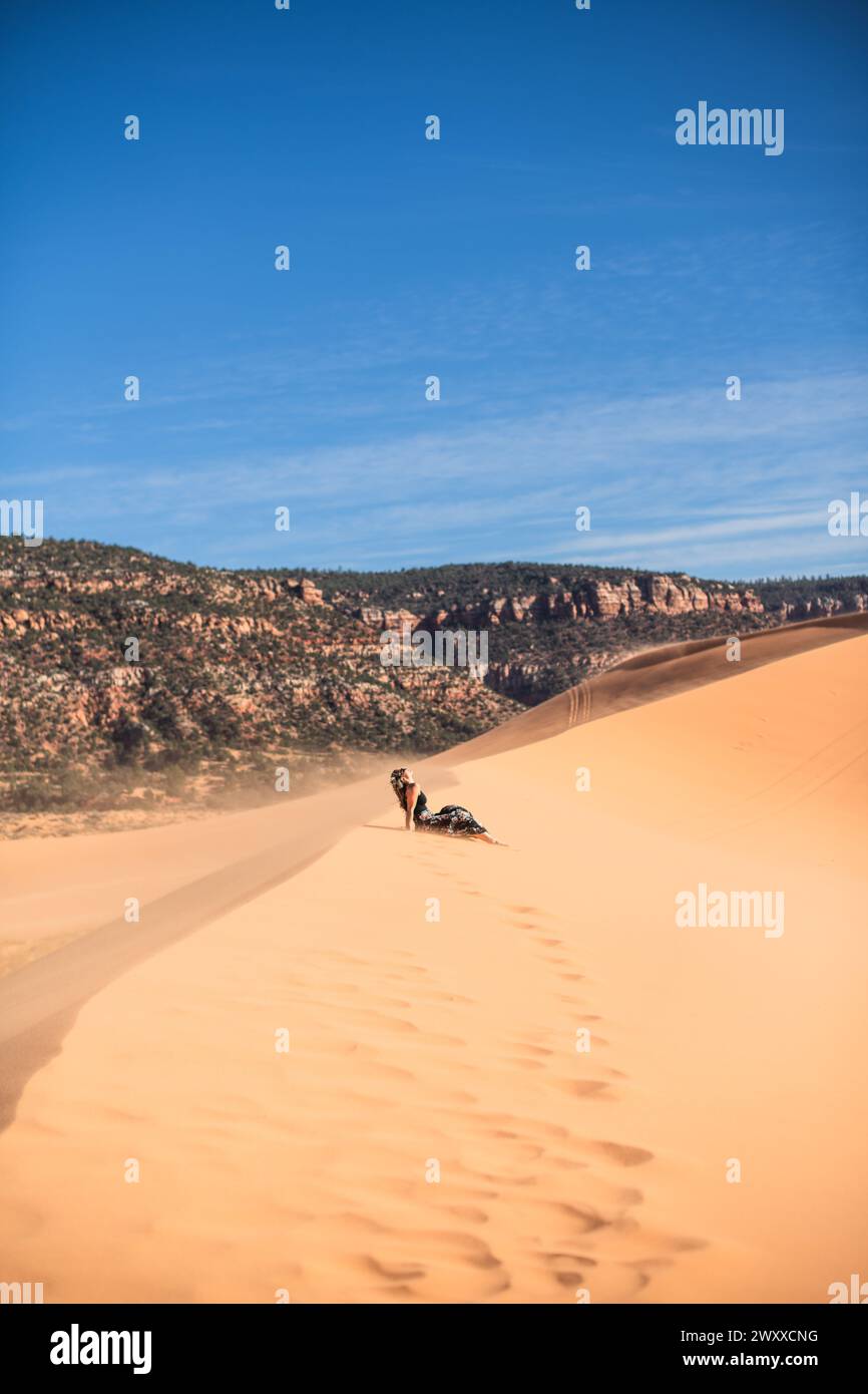 Woman walking on a sand dune in the desert in Coral Pink Sand Dunes ...