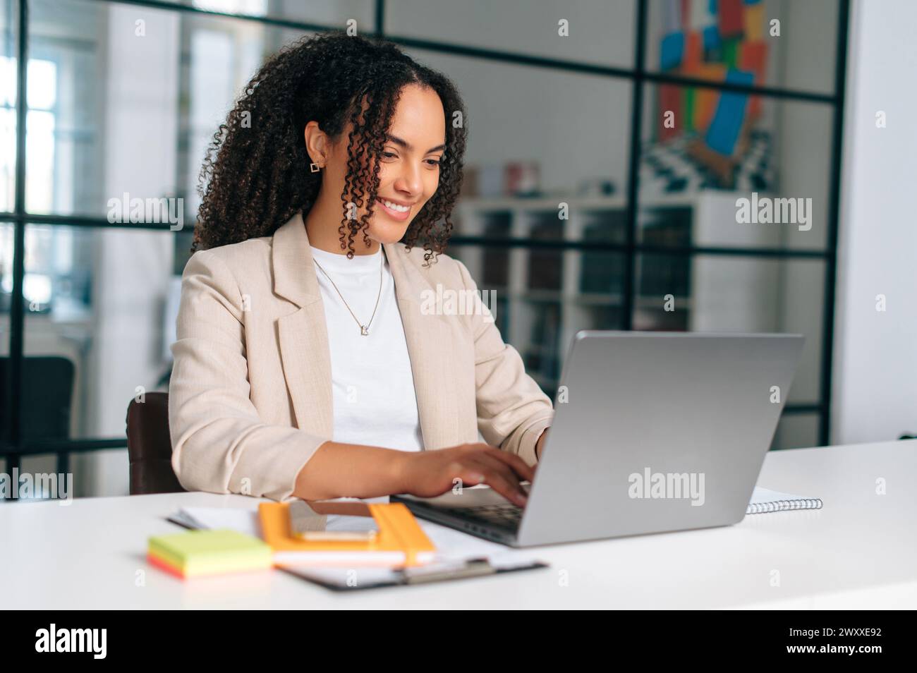 Working in the office. Positive business lady working on laptop in ...