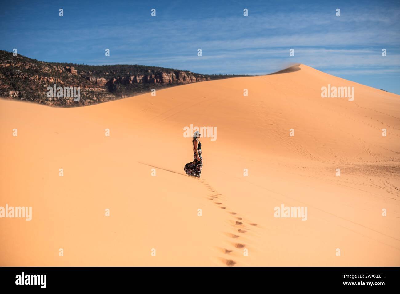 Woman walking on a sand dune in the desert in Coral Pink Sand Dunes ...