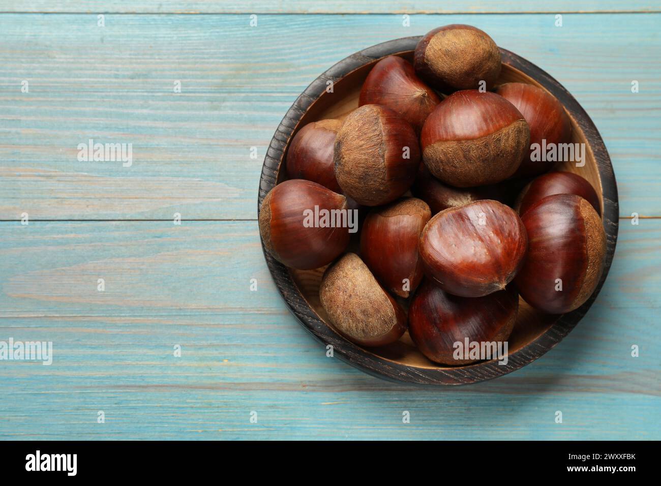 Roasted edible sweet chestnuts on light blue wooden table, top view ...