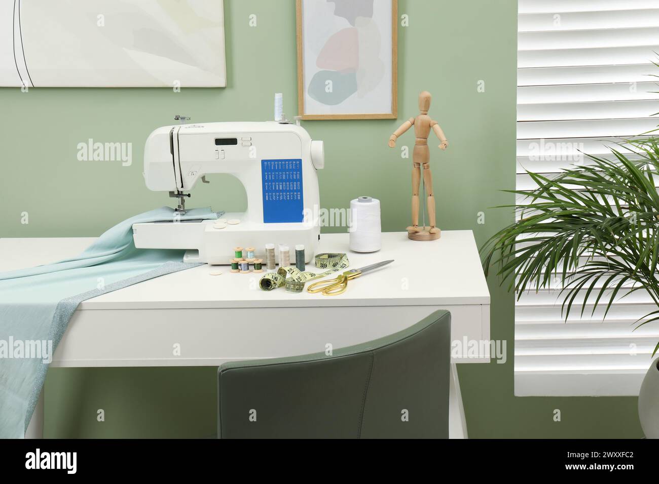 Modern sewing machine with cloth and craft accessories on white table ...