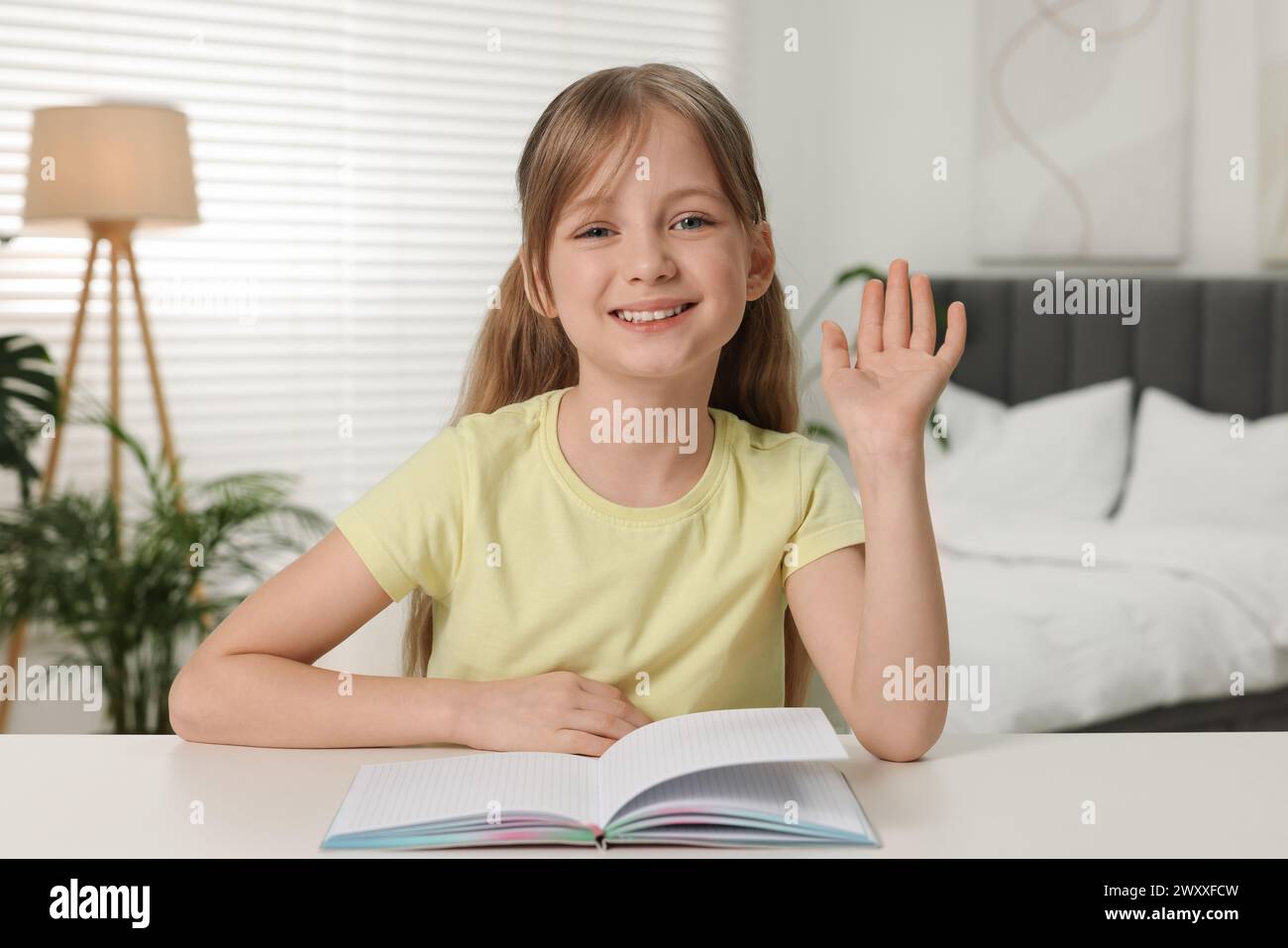 Happy little girl waving hello during online lesson indoors, view from ...