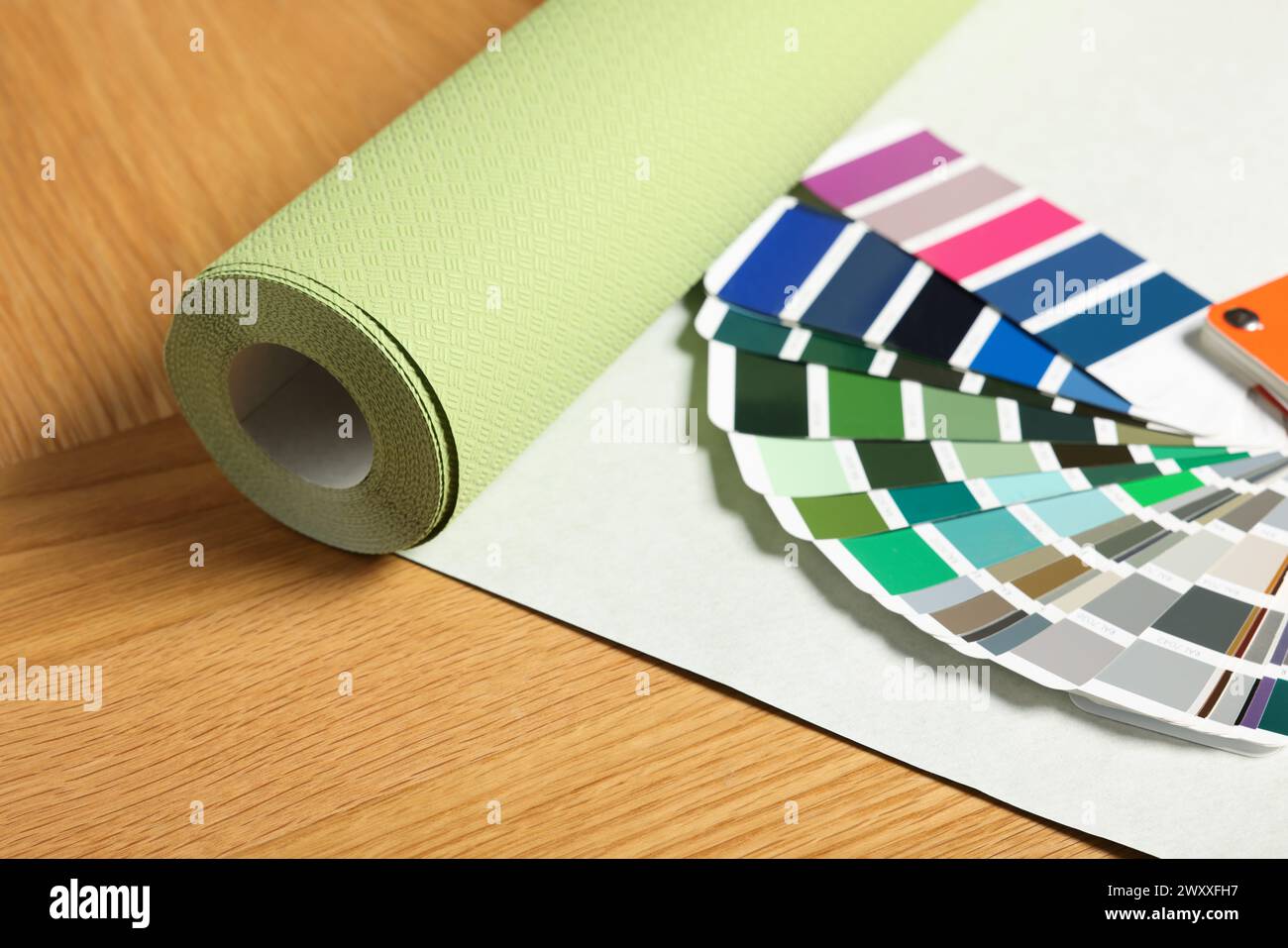 Green wallpaper roll and color palette samples on wooden table Stock ...