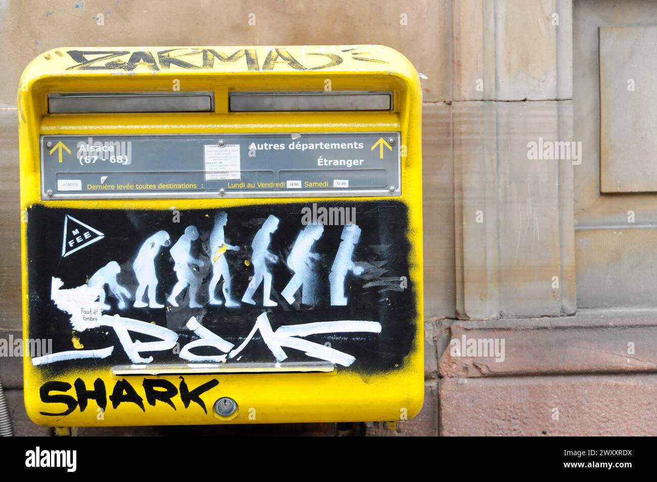 Yellow letterbox smeared with evolution theory graffiti and stickers ...