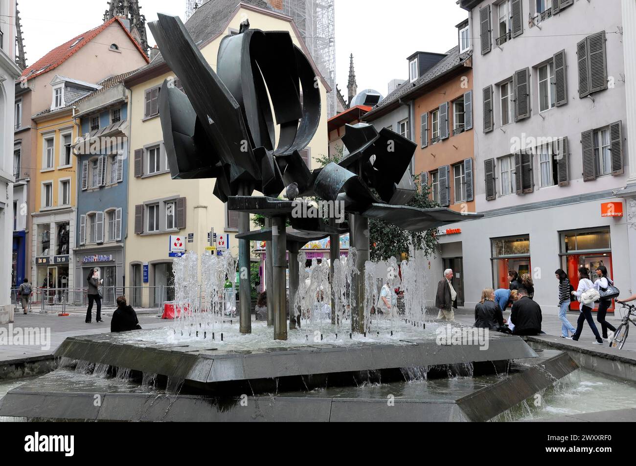 A modern fountain with an abstract sculpture in the heart of a bustling ...