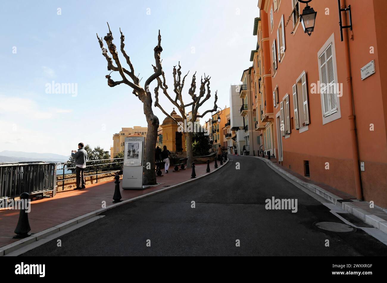 People walking along a Mediterranean street next to traditional houses ...
