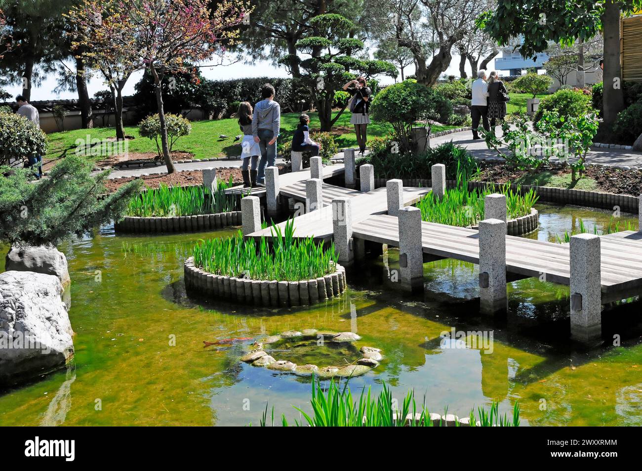Japanese garden, Monte Carlo, Monaco, Cote d'Azur, A family walks on a footbridge over a pond ...