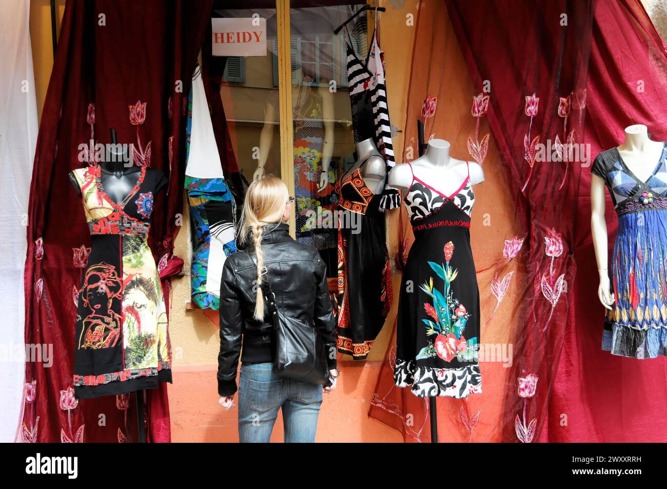 View of a clothes shop with various items of clothing in the window ...