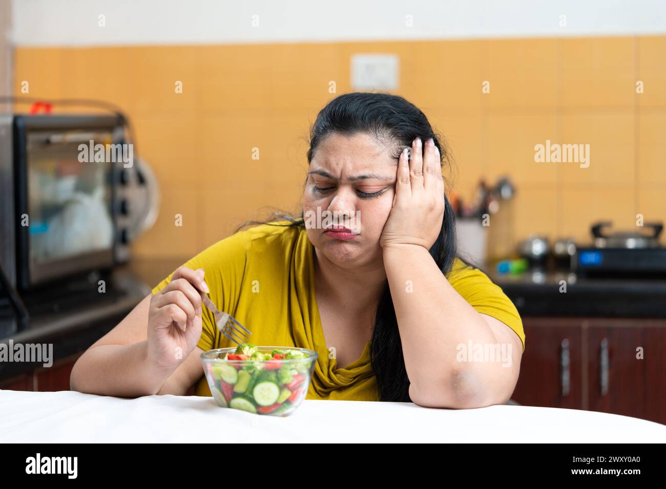 Sad Overweight fat indian woman looking at a bowl of salad while ...