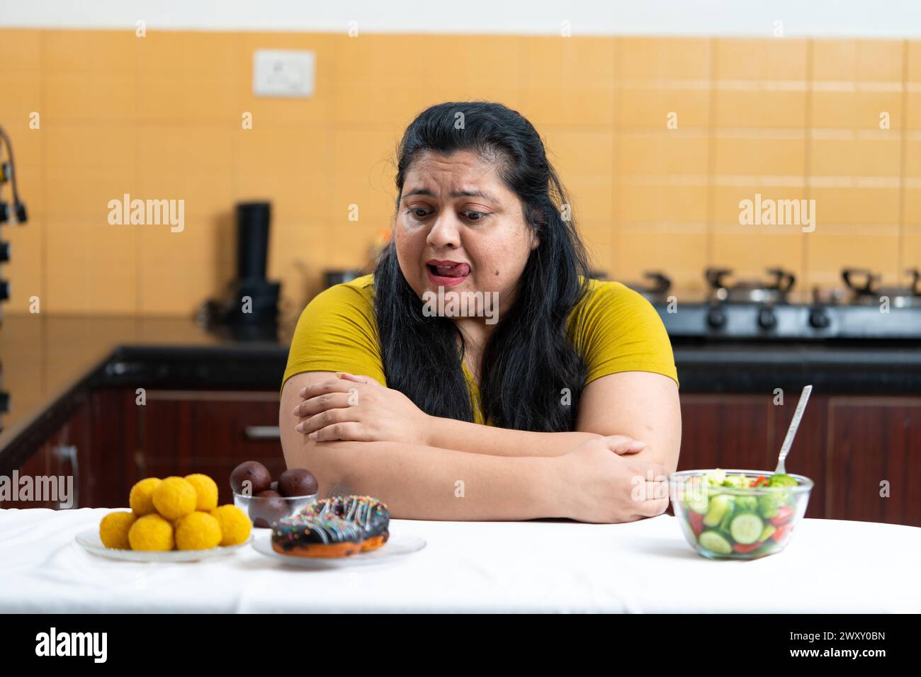 Overweight fat indian woman excited to see donuts and laddu or dessert ...