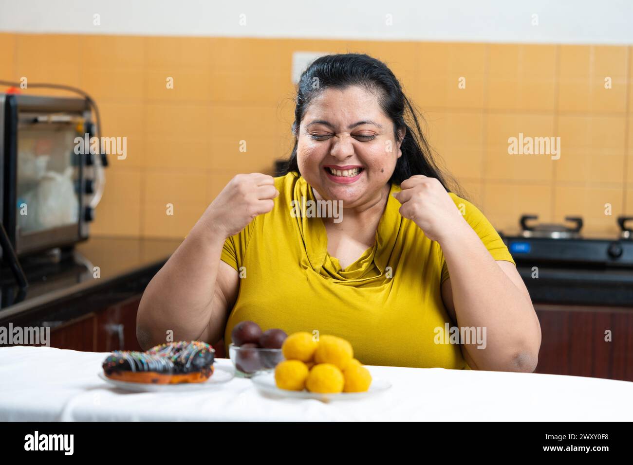 Overweight fat indian woman getting excited to see donuts and laddu or ...