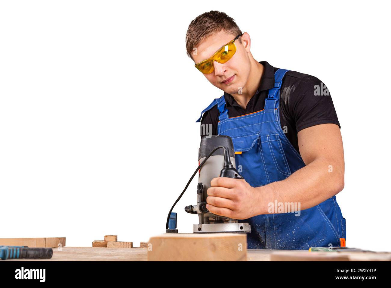 A young man wearing safety goggles carpenter builder pre-works the ...
