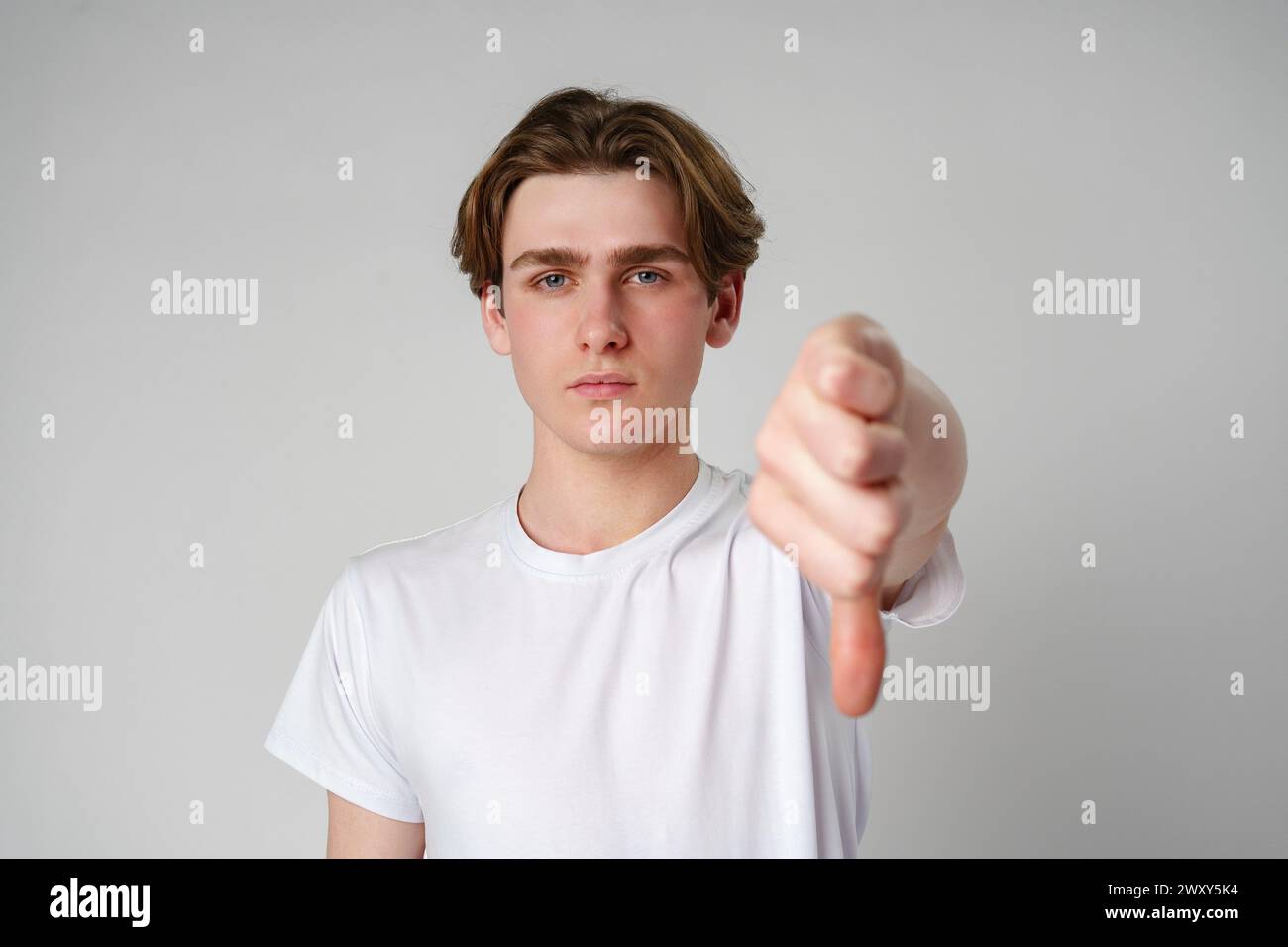 Young Man Giving a Thumbs Down Gesture Against a White Background Stock ...