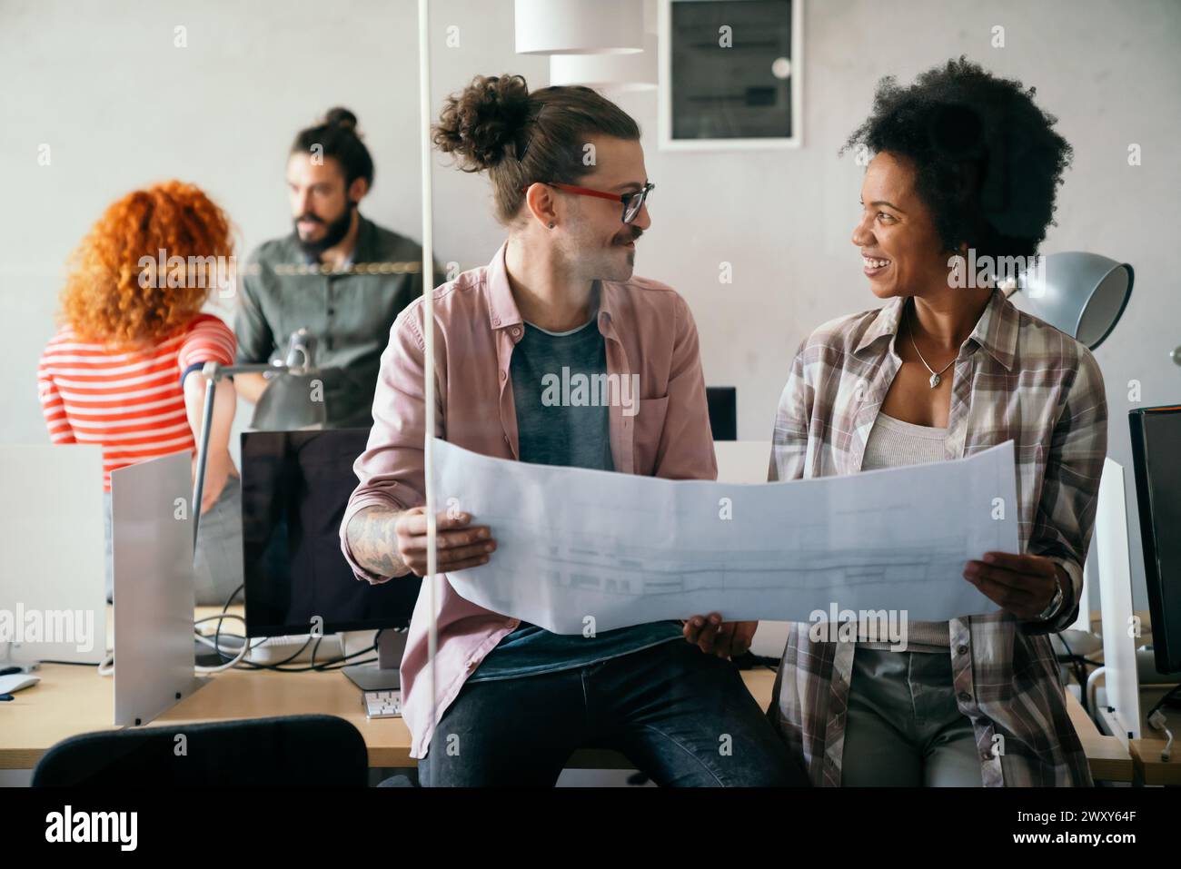 Engineers helping design work on blueprints, collaborate on structural ...