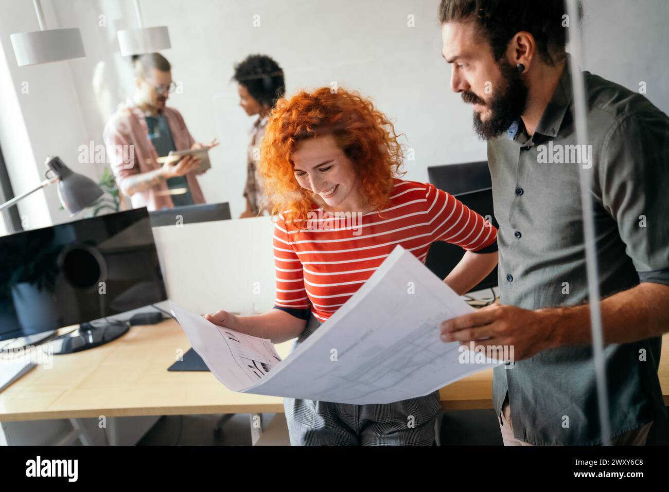 Happy businesspeople laughing while collaborating on a new project in an office. Business ...