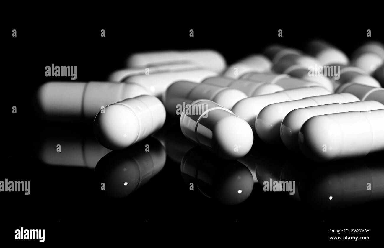 Macro Close up of white painkiller capsule on a reflective black ...