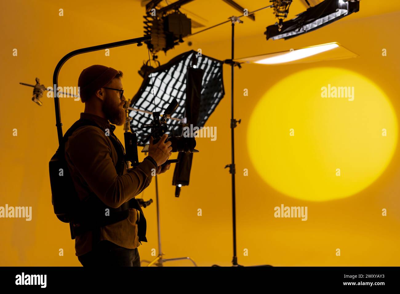 Man capturing large yellow background with camera at film studio Stock ...