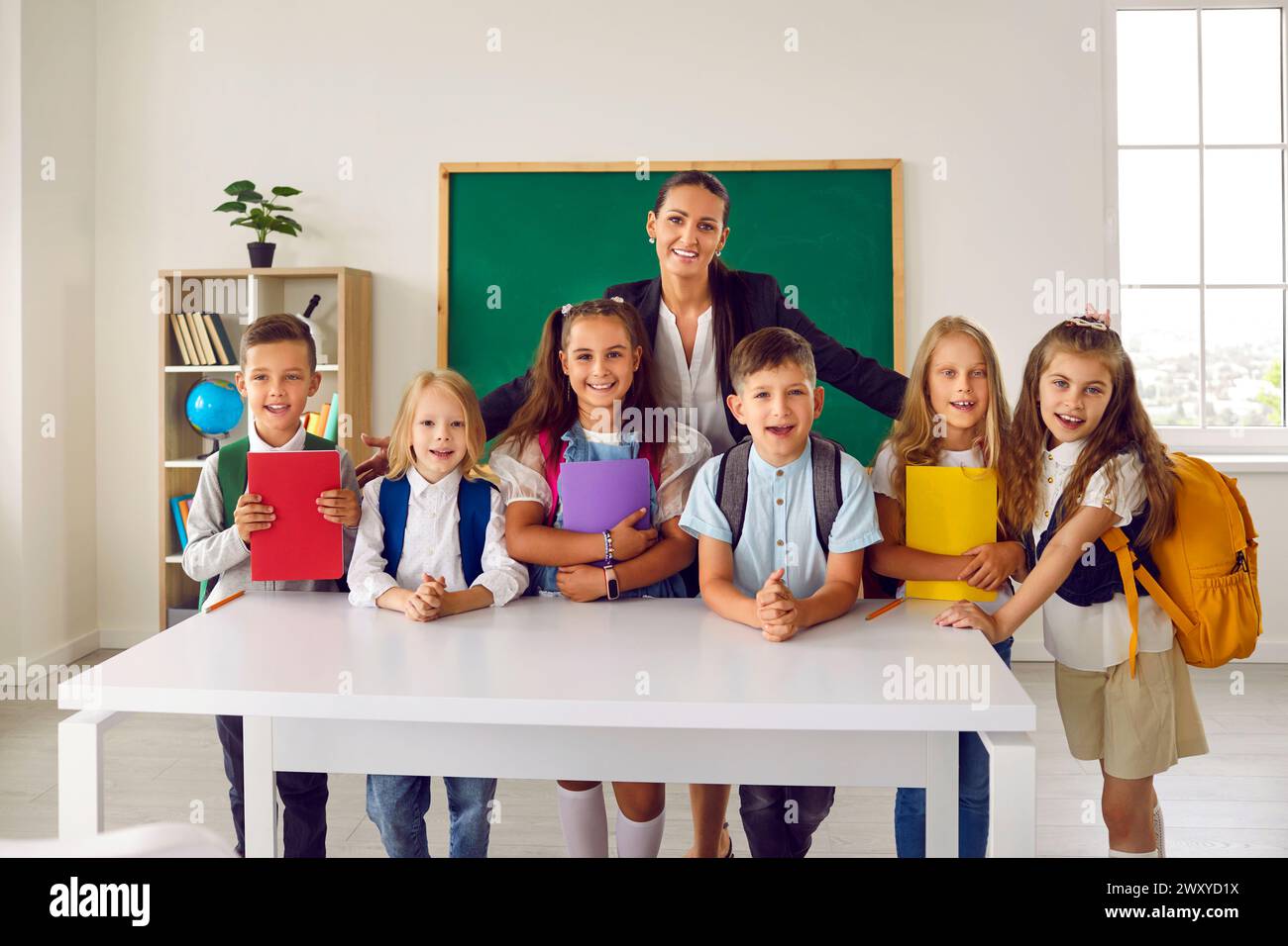 Group portrait of first graders with friendly female teacher in school ...