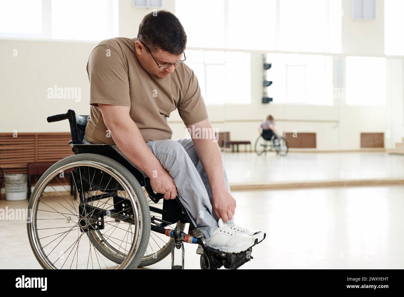 Mature man with disability in wheelchair fixing his leg before dance ...
