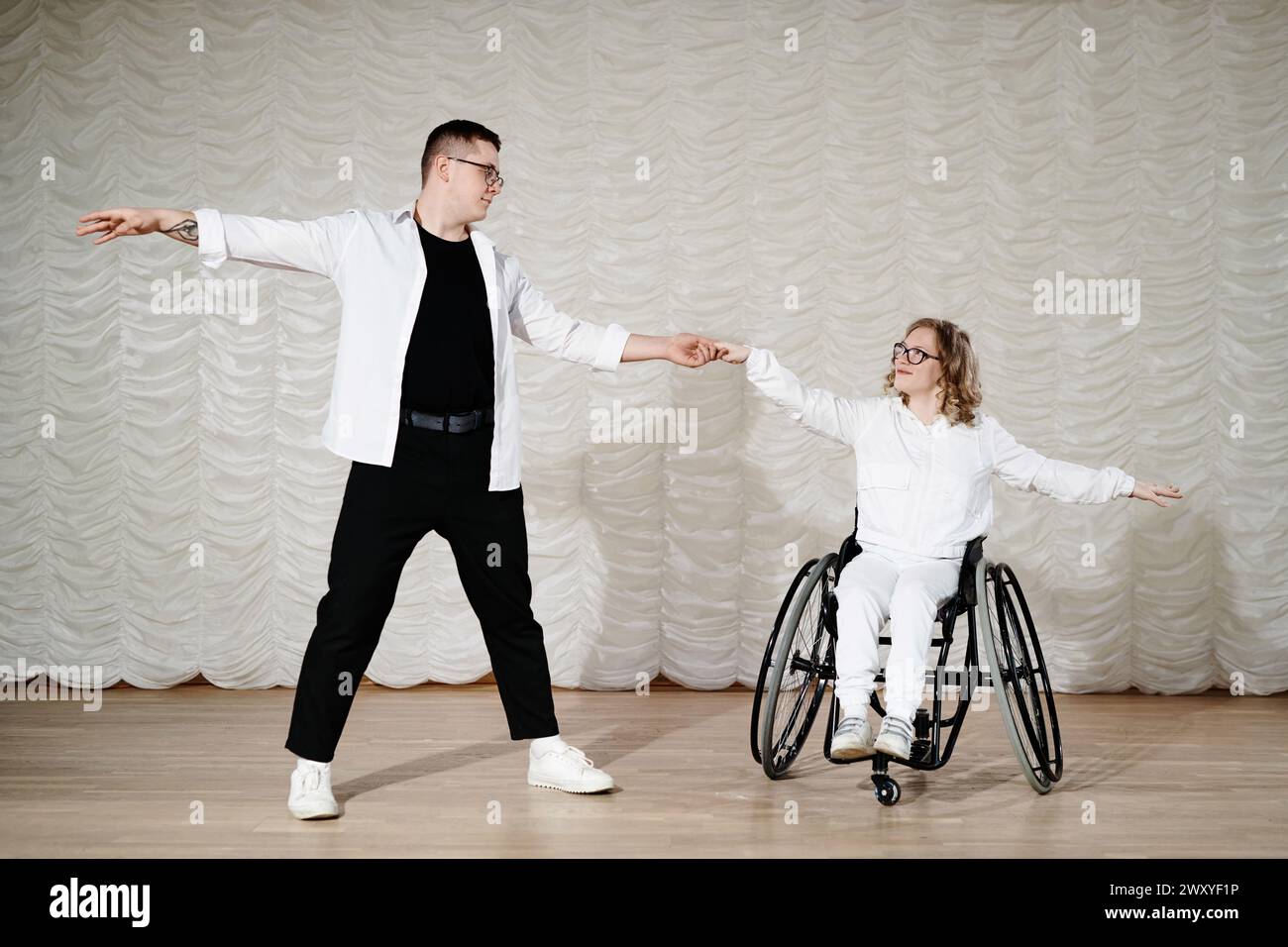 Long shot of young man and woman with disability in wheelchair ...