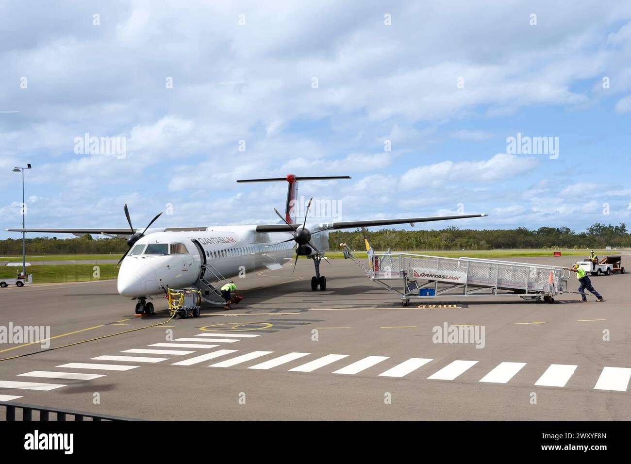 Airport ground staff pushing mobile stairs to the Qantaslink Dash 8 ...