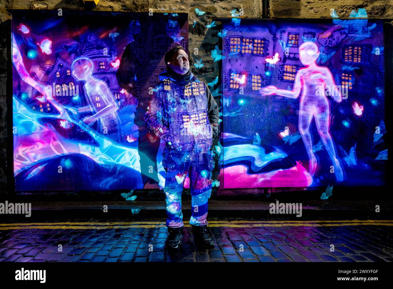 Artist Brian McFeely (aka Elph) stands alongside a multi-panel animated ...