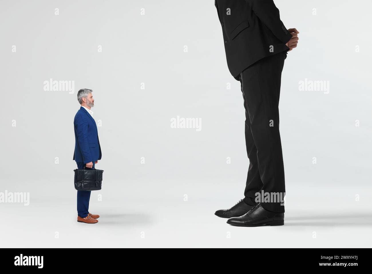 Giant boss and small man on light background Stock Photo - Alamy