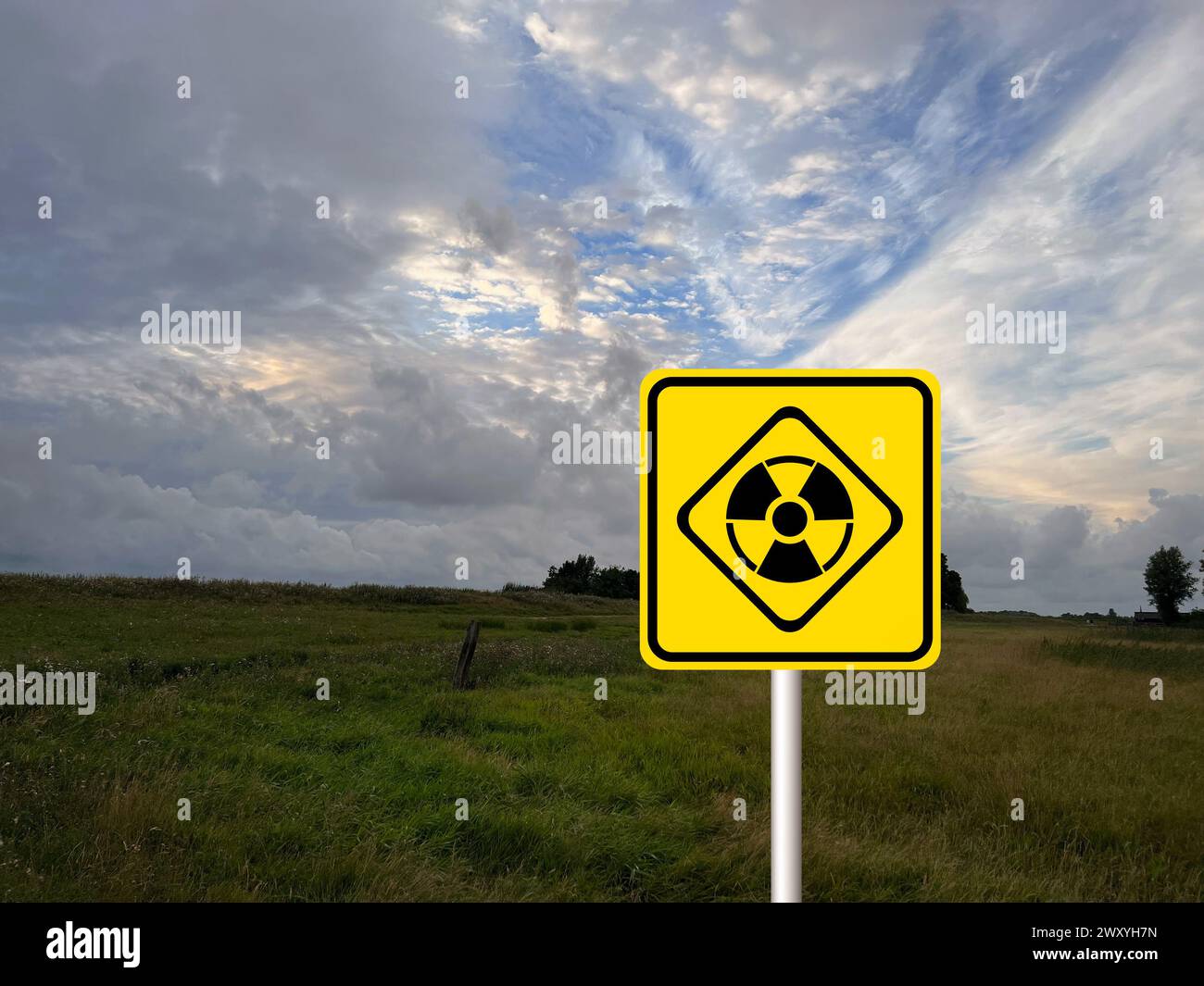 Radioactive pollution. Yellow warning sign with hazard symbol in rural ... Radioactive pollution. Yellow warning sign with hazard symbol in rural ...