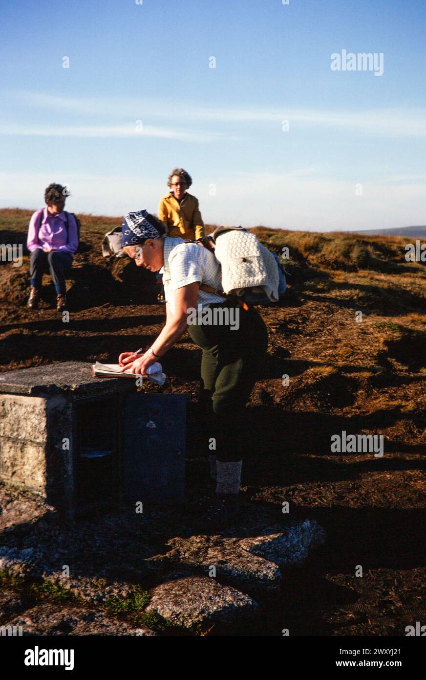 Visitor signing visitors' book, Cranmere Pool letterbox, Dartmoor ...