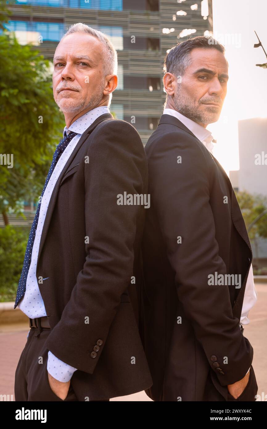 Vertical portrait two successful businessmen standing back to back ...