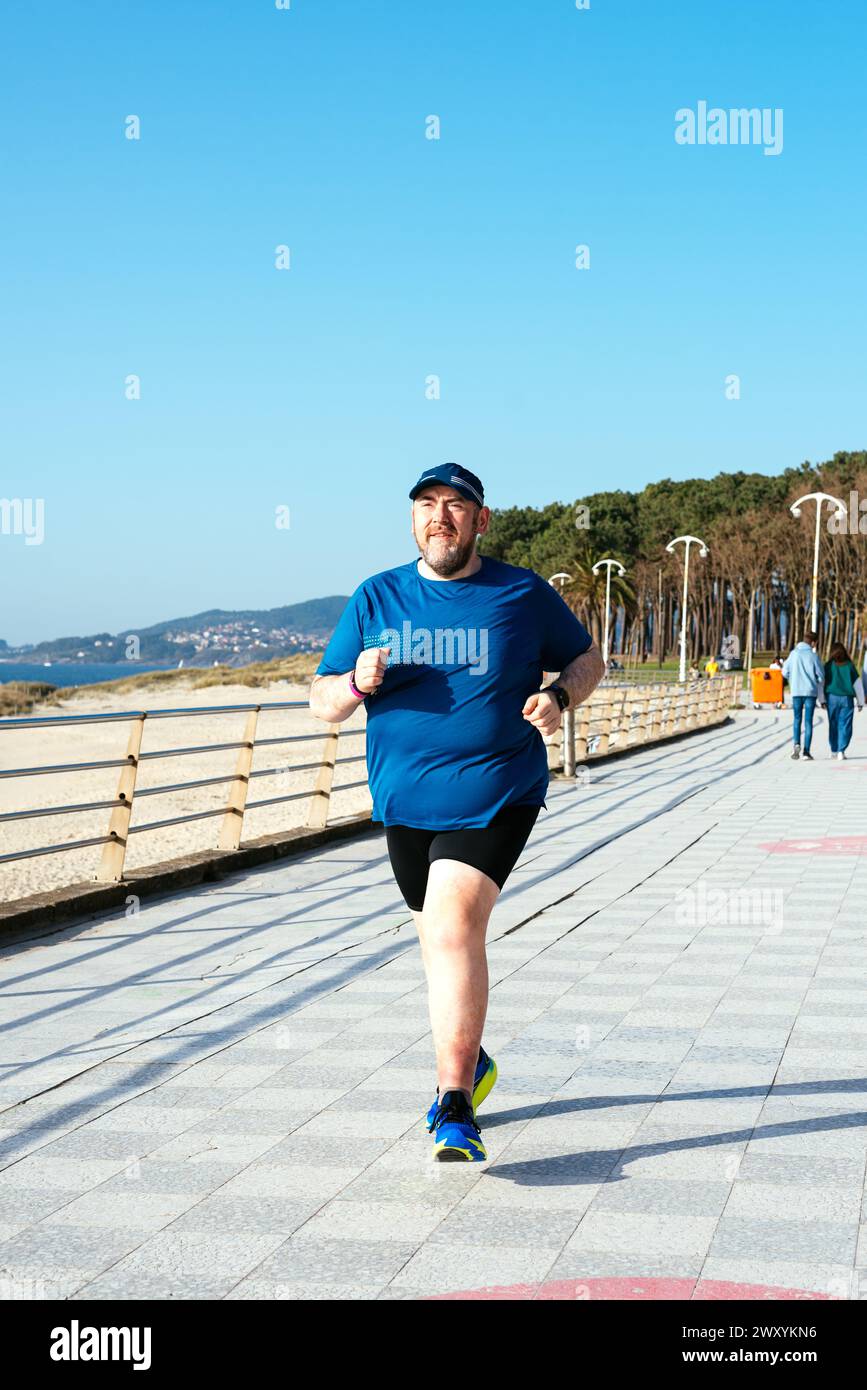 Man in a blue shirt and cap jogging by the sea on a clear day ...