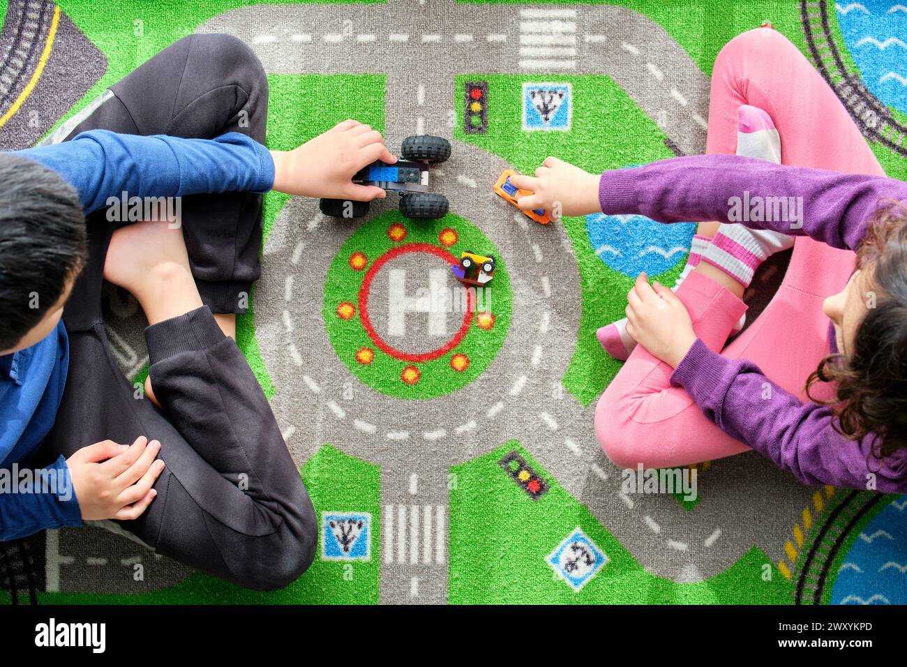 Overhead view of a boy and girl playing with toy cars on a vibrant ...